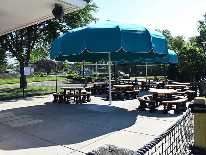 Shaded tables await hungry swimmers, where chlorine-tinged appetites meet classic summer fare in perfect harmony.