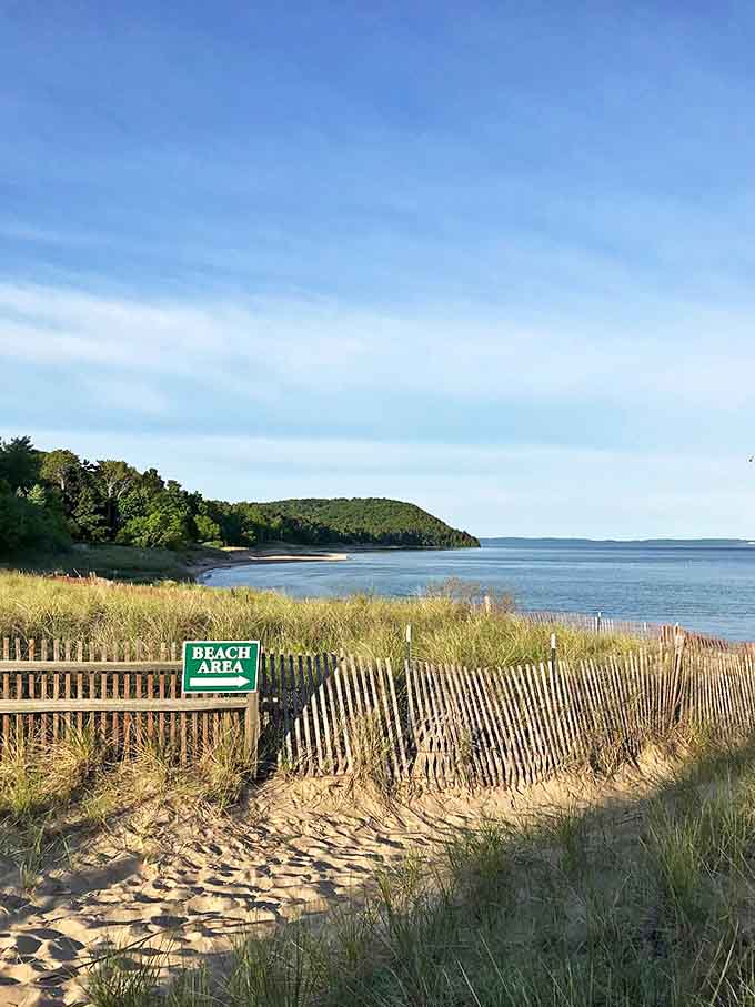Sandy pathways lead to hidden shoreline treasures, where Lake Michigan awaits beyond the dune grass sentinels.