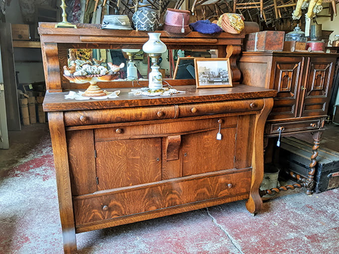 This antique dresser tells stories through its worn drawer pulls and rich wood grain – each scratch represents a moment in its century-long journey.