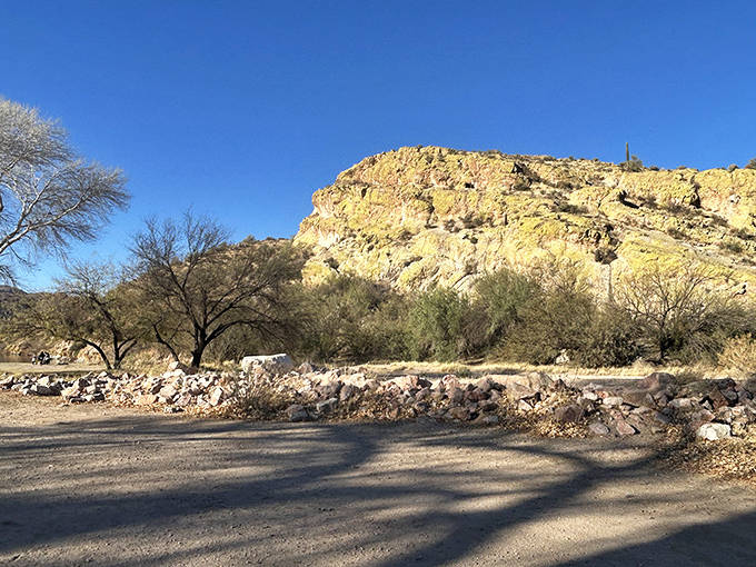 Rugged mountain formations create a dramatic backdrop for beachgoers, their golden hues changing with each hour of desert sunlight.