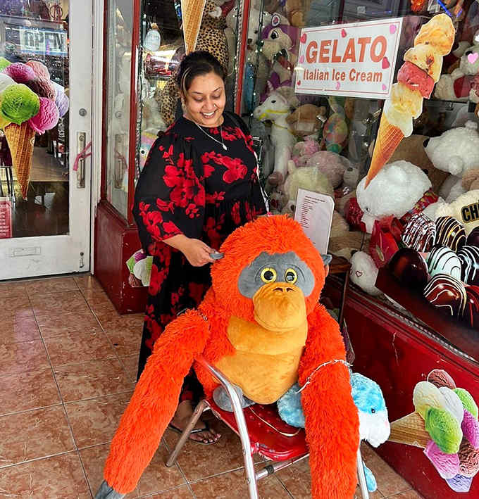 A staff member shares the shop's magic with visitors, surrounded by the plush toy audience that watches over all sweet transactions.