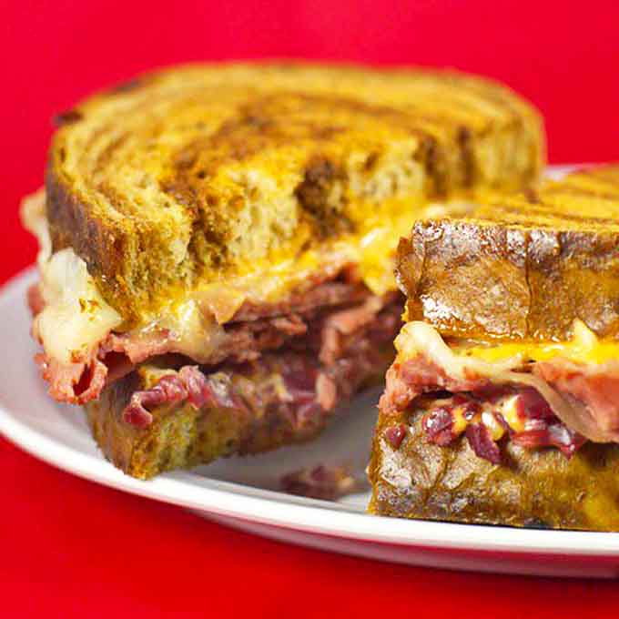 The Reuben that launched a thousand sighs – perfectly grilled marble rye hugging corned beef, sauerkraut, and Swiss in a dance of delicious harmony.