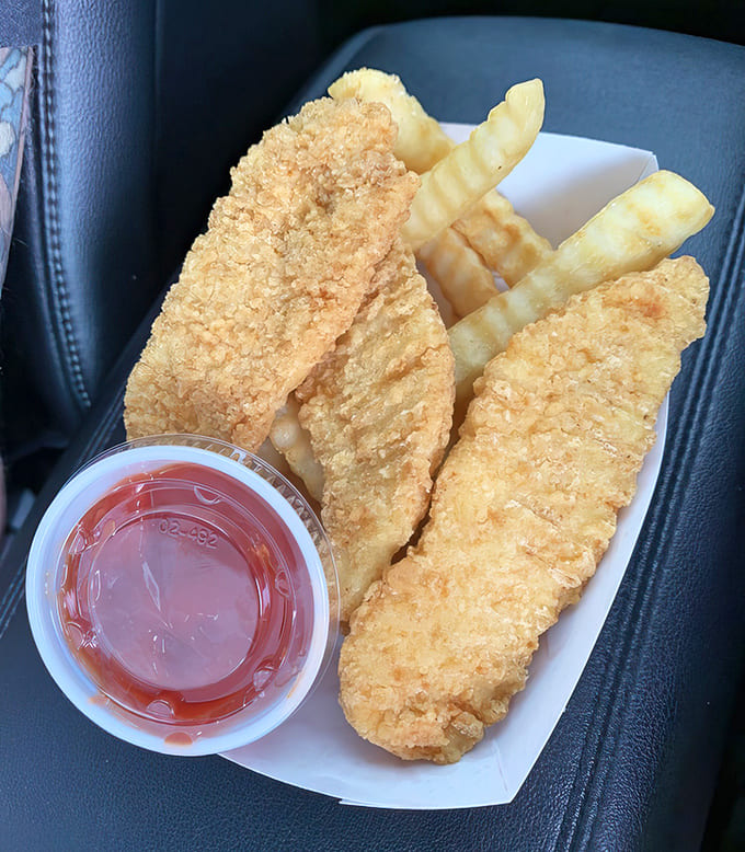 Golden-fried chicken strips with crinkle-cut fries make the perfect portable feast, crispy on the outside and tender within – comfort food defined.