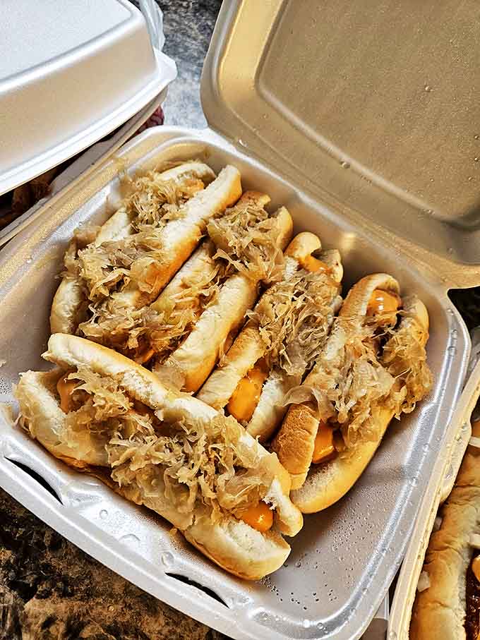 A battalion of dogs nestled in their takeout container, each one topped with tangy kraut that somehow makes everything better.
