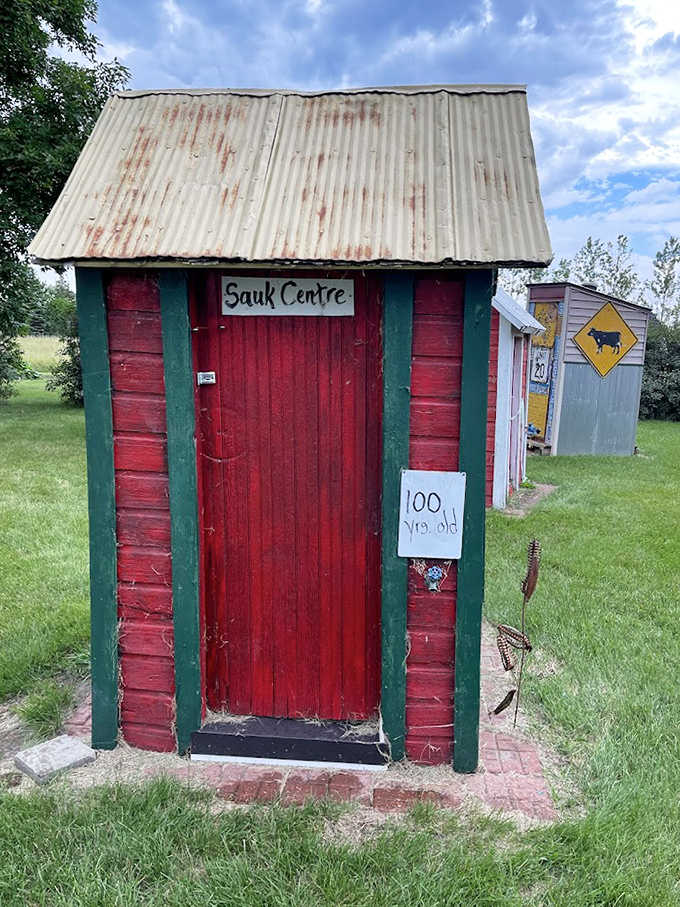 The century-old Sauk Centre outhouse, painted bright red with green trim, stands as a colorful monument to Minnesota's bathroom history.