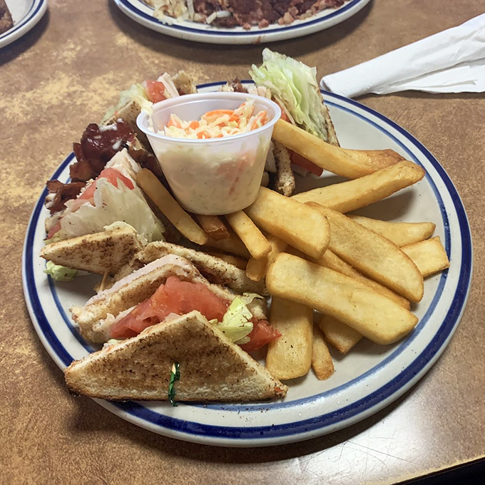 The club sandwich stands tall as an architectural marvel of turkey, crisp vegetables, and bacon, requiring both hands and possibly a strategy.