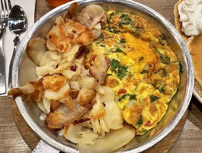 The vegetarian omelette arrives in its own skillet, a fluffy egg creation packed with colorful vegetables and melted cheese.