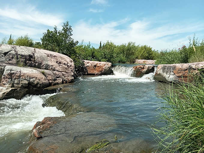 Refreshing respite: Crystal clear waters tumble over smooth stones, creating a surprising waterfall scene in the heart of prairie country.