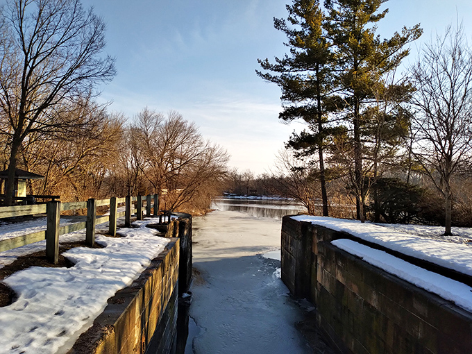 Winter transforms the canal into a frozen timeline, where summer's flowing waters pause, creating a serene, crystalline landscape.