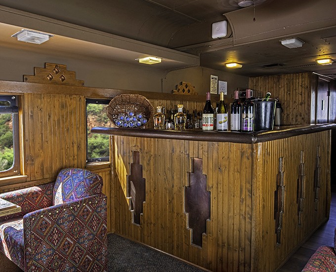 The bar car's rustic wood paneling and Southwestern touches create the perfect backdrop for toasting to views that no roadside overlook can match.