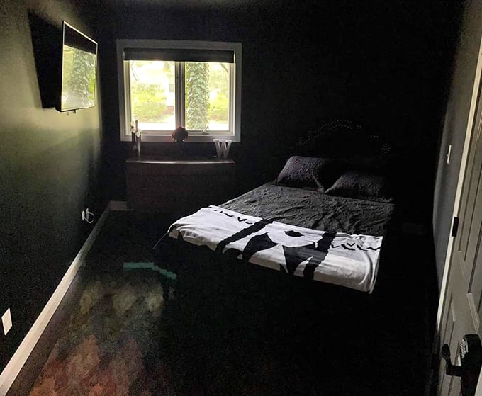 Monochromatic magic in the bedroom, where black walls create a cocoon-like space perfect for vampire-quality slumber.