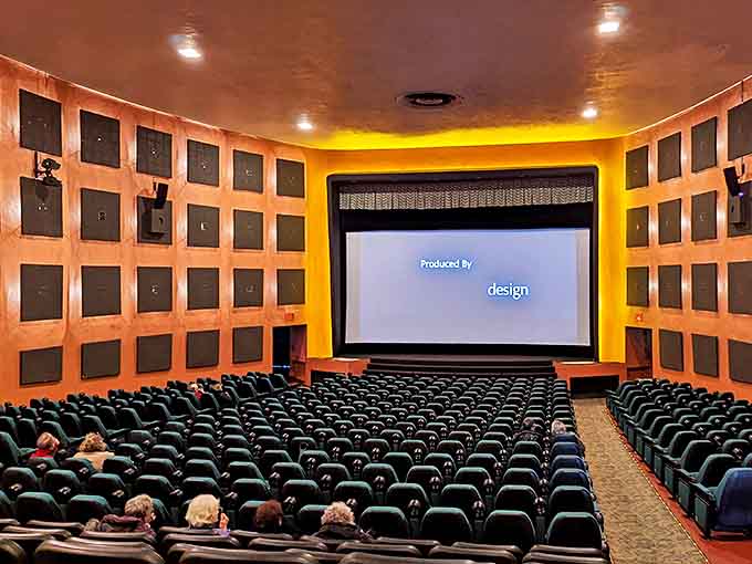 The main screen commands attention in the orange-walled auditorium, where digital projection meets mid-century design in perfect harmony.