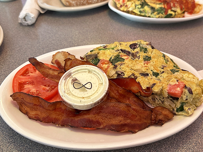 A breakfast plate that speaks volumes &ndash; fluffy eggs, crispy bacon, and fresh tomato slices create a colorful morning masterpiece.