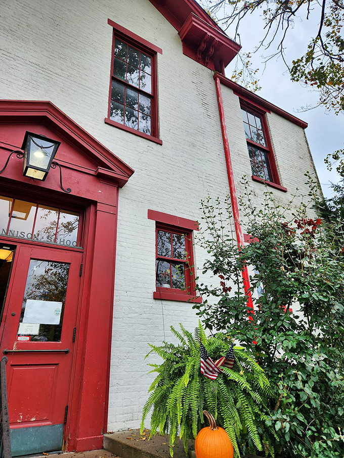 The welcoming red door and fern-adorned entrance invite you into a dining experience steeped in history and charm.