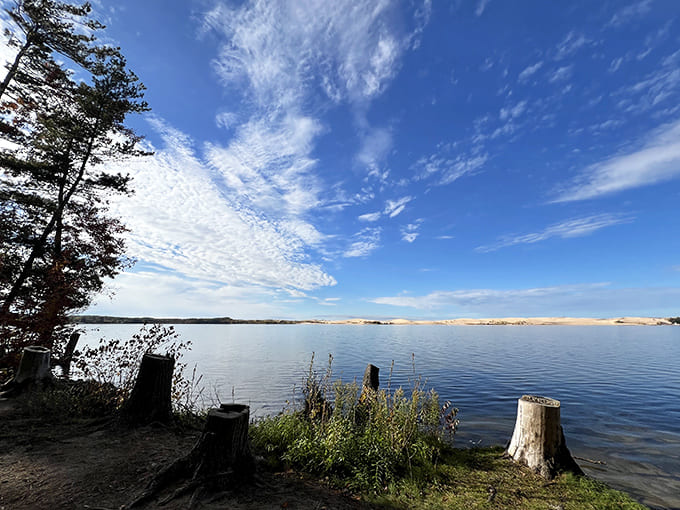 The vast expanse of water stretches toward the horizon, where sky meets lake in a seamless blue canvas punctuated by wispy clouds.