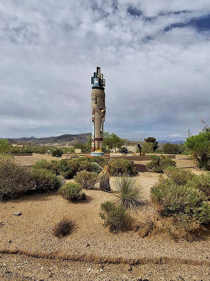 Desert vegetation creates a natural garden surrounding the statue, highlighting native Sonoran plant species.