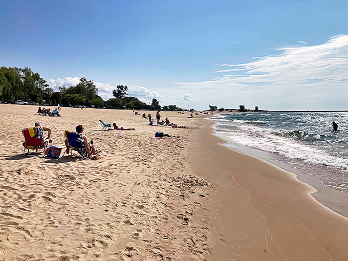 Beach visitors spread out along the shoreline, each creating their own little kingdom of umbrellas, coolers, and questionable sunscreen application techniques.