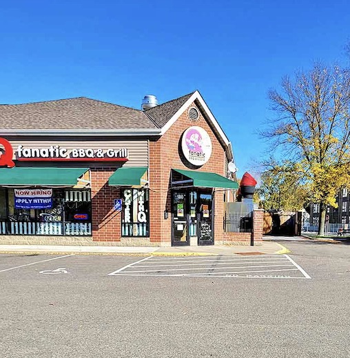 Q Fanatic's exterior on a perfect Minnesota day, the green awnings and brick facade hiding the smoky paradise within.