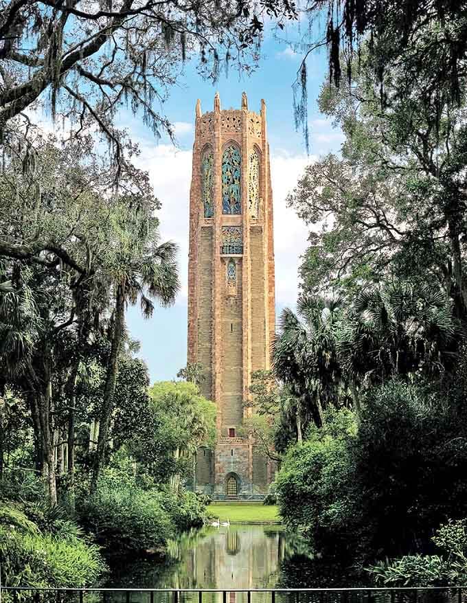 The majestic Singing Tower rises like a medieval fantasy through Spanish moss-draped trees, its pink marble glowing in Florida sunshine.