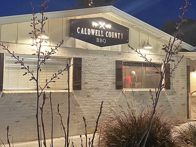 The white-brick exterior of Caldwell County BBQ glows invitingly at dusk, a beacon for barbecue pilgrims seeking smoky salvation in Gilbert.