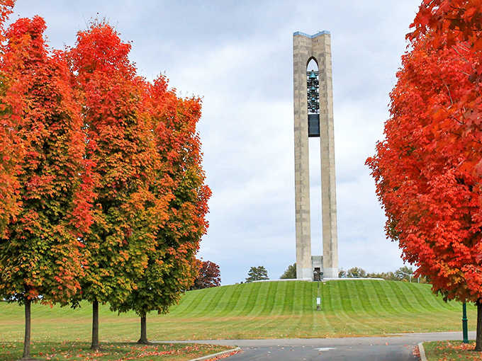 The Carillon Tower stands majestically among fiery autumn foliage, its limestone structure reaching skyward like a historical exclamation point on Dayton's innovative landscape.