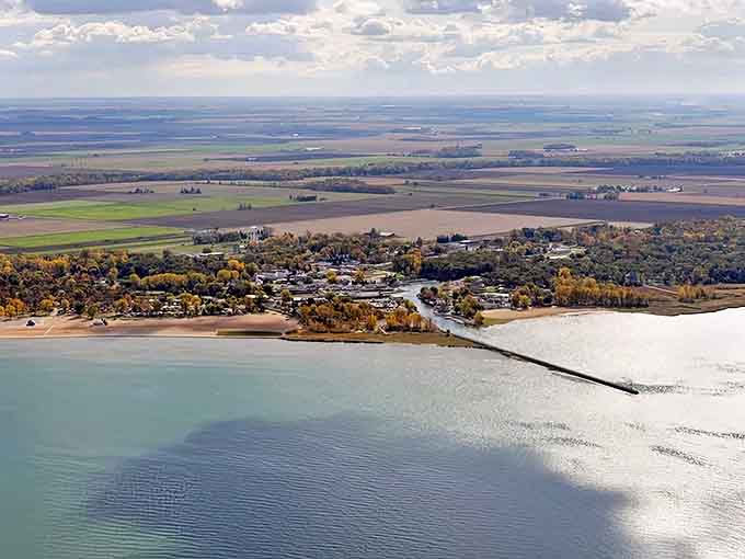 Aerial view of Caseville reveals nature's perfect balance: endless blue waters meeting golden farmlands under Michigan's vast sky.