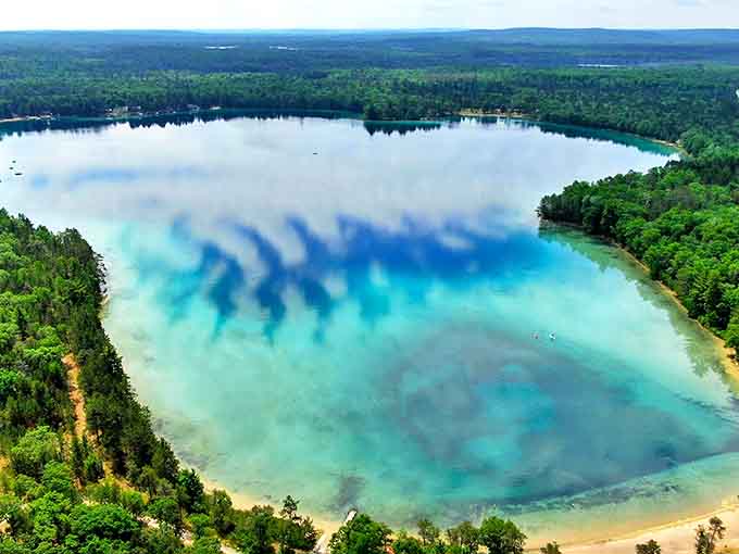An aerial view of Clear Lake that reveals why it earned its name &ndash; crystal-clear turquoise waters surrounded by Michigan's lush forests create a postcard-perfect scene.