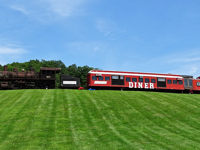 A vintage locomotive stands guard beside the vibrant red diner car, welcoming hungry travelers to this roadside slice of Americana.