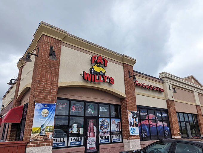 The bright red Fat Willy's sign featuring that classic yellow hot rod practically jumps off the building, promising automotive nostalgia and mouthwatering meals inside.