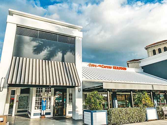 The pristine white exterior of Cod & Capers beckons seafood lovers with its distinctive striped awnings and promise of ocean-fresh delights.