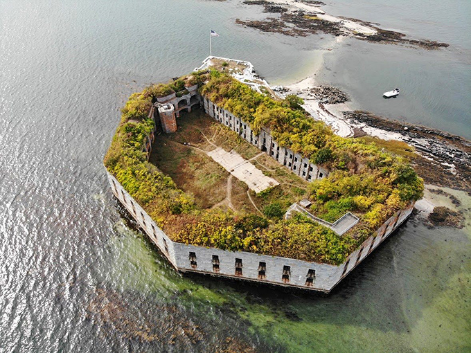 Fort Gorges stands as a hexagonal sentinel in Casco Bay, its granite walls now crowned with greenery after more than a century of solitude.