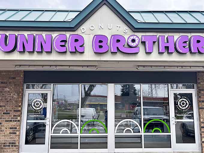 Exterior: The vibrant purple sign of Funner Brothers Donut Company beckons like a beacon of sugary hope on an otherwise ordinary street.