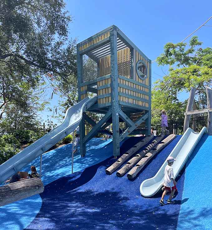 The vibrant blue playground surface creates an ocean-like setting where imagination meets adventure at the Glazer Family Playground.
