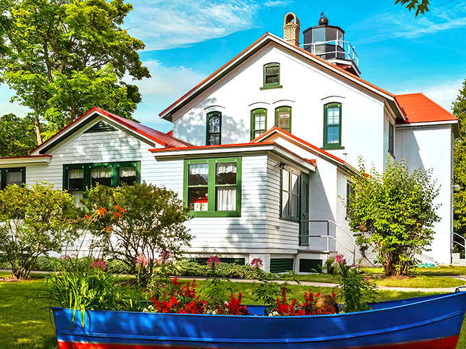 The Grand Traverse Lighthouse stands proudly against a brilliant blue Michigan sky, its white walls and red roof creating a postcard-perfect scene.