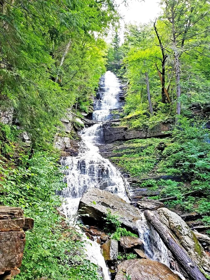 Lye Brook Falls cascades 125 feet down striated rock faces, nature's own multi-tiered masterpiece hidden in Vermont's emerald embrace.