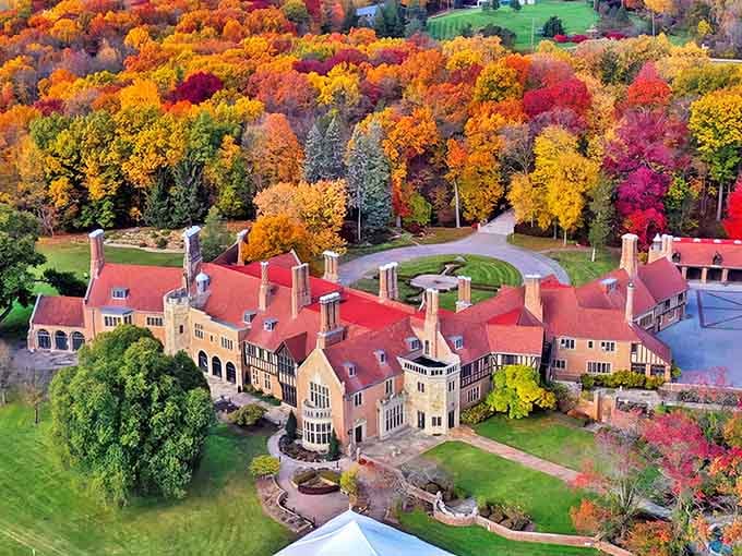 Meadow Brook Hall stands majestically amid autumn's fiery display, like a Tudor castle that somehow landed in Michigan instead of the English countryside.