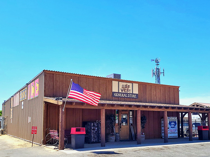 The wooden facade of Out West General Store stands proudly against Arizona's blue sky, an American flag fluttering above like a welcome beacon to weary travelers.