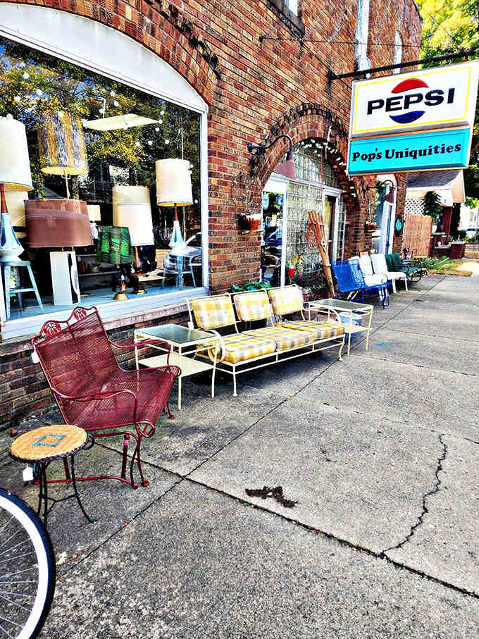 The brick storefront of Pop's Uniquities beckons with vintage charm, mid-century patio furniture creating an impromptu living room right on the sidewalk.