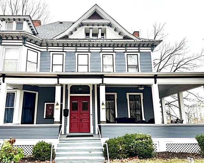 The striking blue exterior with its bold red door invites visitors into a Victorian fantasy, complete with wrap-around porch perfect for morning contemplation.