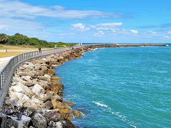 Sebastian Inlet's rocky jetty stretches into turquoise waters like nature's own runway, where waves crash dramatically against ancient stones.