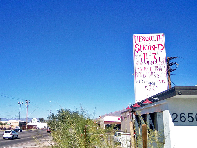 The weathered "MESQUITE SMOKED BBQ" sign stands as a beacon for hungry souls seeking authentic barbecue in Tucson's desert landscape.