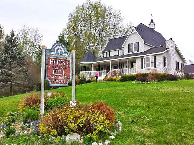 The House on the Hill stands proudly against Michigan's sky, its white farmhouse charm and welcoming porch promising a retreat that feels like coming home.