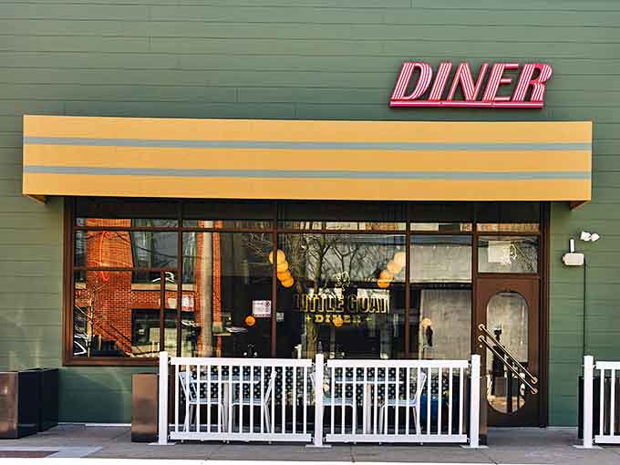 The inviting green exterior of Little Goat Diner beckons with its classic neon sign, promising comfort food with a creative twist.