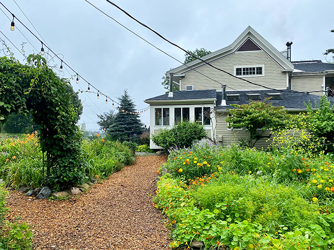 A garden path winds through vibrant flowers and vegetables, leading to Primo's charming farmhouse &ndash; where your dinner was likely growing just hours ago.
