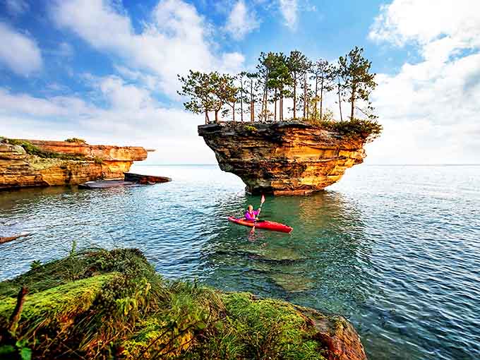 Turnip Rock stands like nature's own bonsai experiment, a limestone island crowned with a perfect miniature forest floating in Lake Huron's crystal waters.
