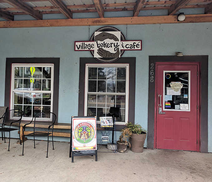 The blue exterior with that inviting red door isn't just a building &ndash; it's a promise of deliciousness waiting inside Village Bakery & Caf&eacute;.