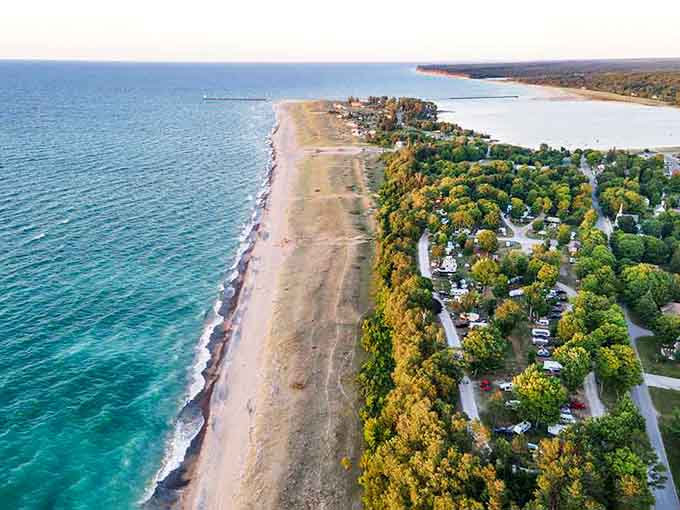 Aerial paradise where forest meets shoreline: Lake Michigan's turquoise waters create nature's perfect boundary with Grand Haven's lush woodland landscape.