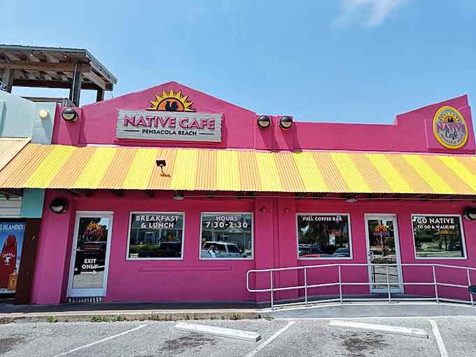 The vibrant pink exterior of Native Cafe stands out like a cheerful beacon against the Pensacola Beach sky, promising culinary delights within its sunny yellow-trimmed walls.
