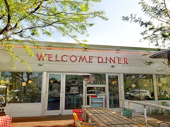 The iconic red neon "WELCOME DINER" sign beckons hungry travelers like a lighthouse for comfort food seekers in Phoenix's urban landscape.
