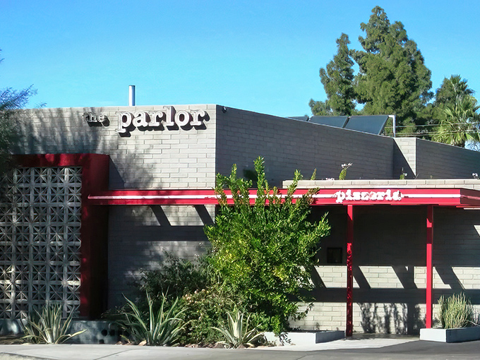 The Parlor's exterior blends mid-century charm with modern flair, its red accents popping against gray brick like a culinary exclamation point.